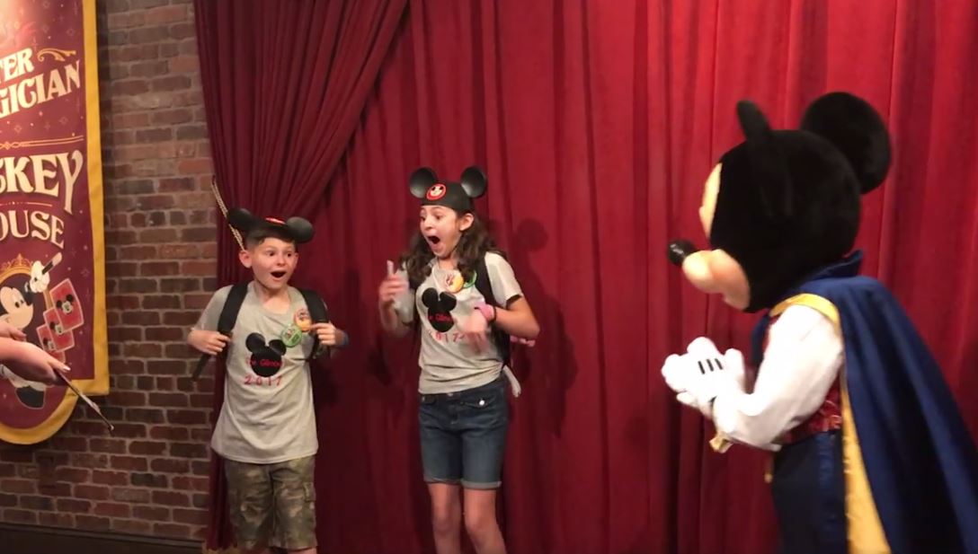 Mickey Mouse hands two siblings a sign... and they can't believe...